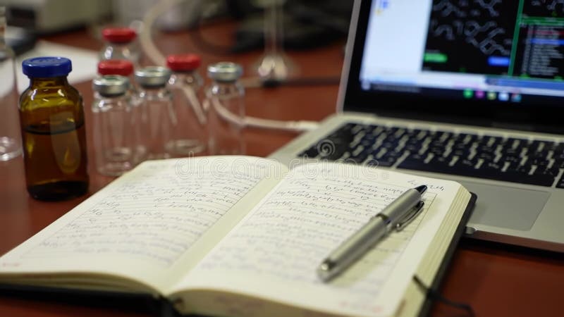 Laboratory Workspace Featuring a Notebook, Pen, and Vials, with a ...