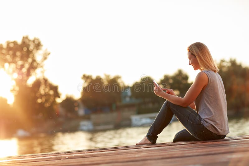 Lady with Phone Enjoying at Sunset on the River Stock Photo - Image of ...