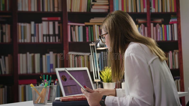 A Lady Using a Laptop and a Tablet in the Library Stock Image - Image ...