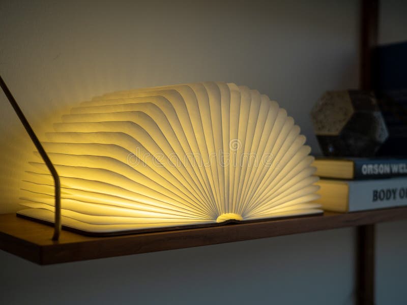 Lamp in the Shape of an Open Book Emits Soft Glow on Shelf Stock Photo ...