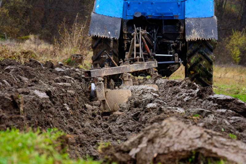 Land Cultivation,tractor Plows the Ground, a Blue Small Tractor and a ...