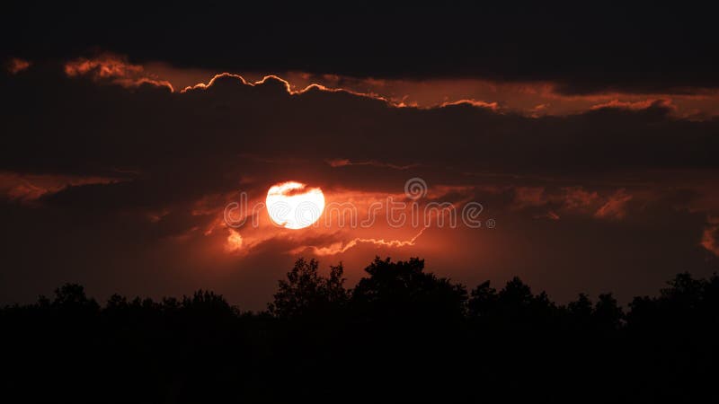 Landscape with Red Sun Setting Behind Dark Clouds Stock Image - Image ...