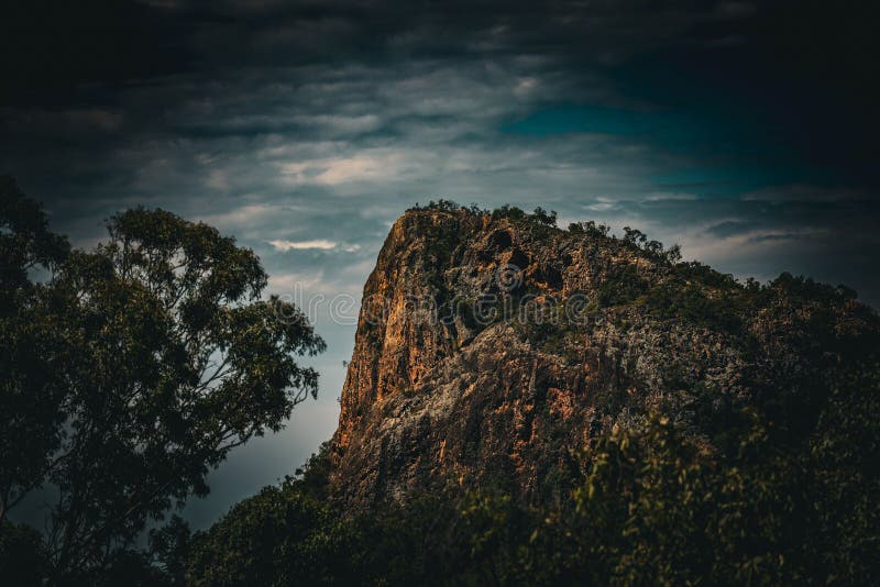 Landscape Scene of Rocky Cliff with Trees Under Dramatic Cloudy Sky ...