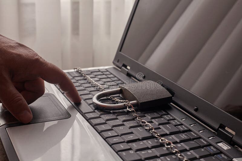 On the Laptop Keyboard Lies a Lock with a Chain. a Finger Presses a Key ...