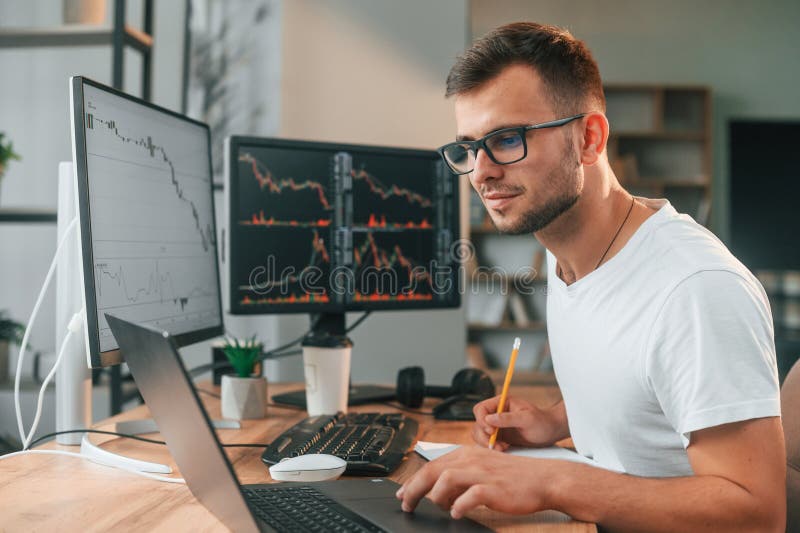 Laptop is on the Table. Young Stock Broker is Working in the Office by ...