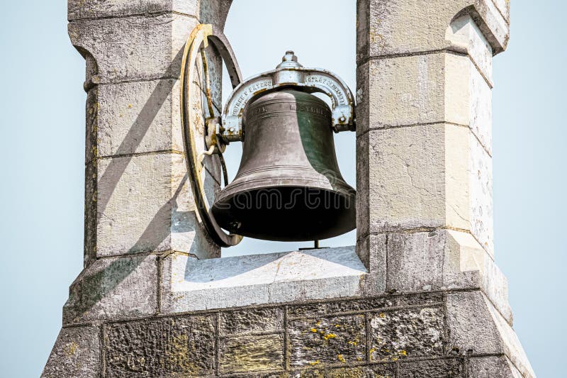 A Large Bell Hangs from a Stone Tower. it is Made of Metal and Has a ...
