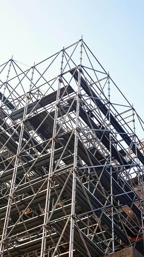 A Large Building Under Construction with Scaffolding Against Blue Sky ...