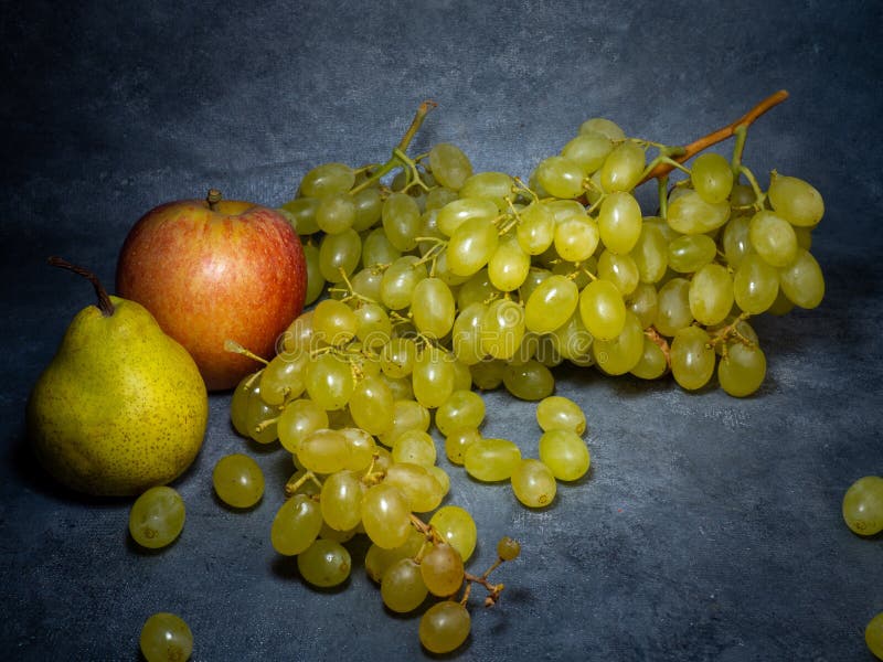 A Large Bunch of Grapes with an Apple and a Pear on a Black Background ...
