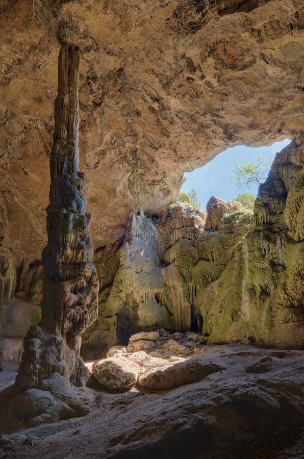 A Large Cave with Rugged Rock Formations and a Tall Stalagmite. Stock ...