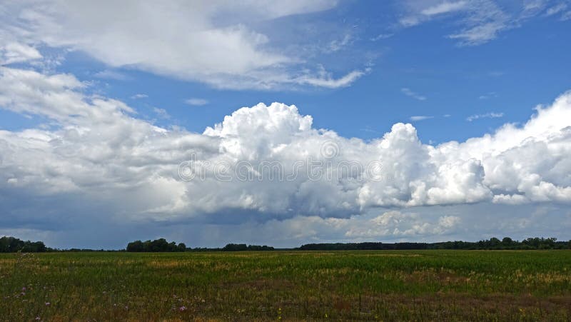 A Large Cloud Floating in the Sky Above the Field. Stock Photo - Image ...