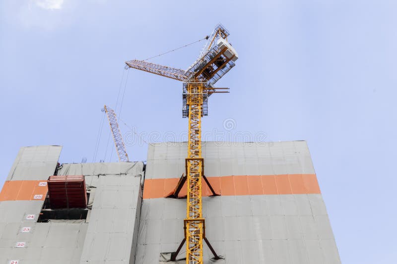 A Large Construction Crane Works on a High-rise Building Construction ...