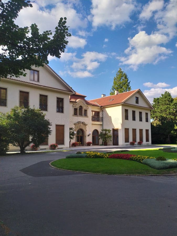 A Large, Elegant Building Featuring a Beige Facade and Red-tiled ...