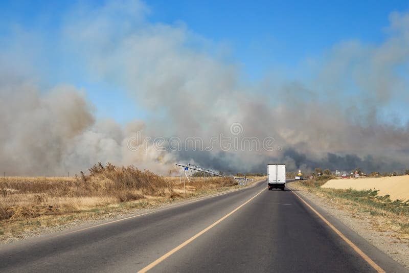 A Large Fire on the Side of the Road with Vehicles Moving. Smoke and ...