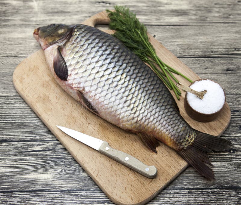 A Large Fresh Carp Live Fish Lying on a Wooden Board with Salt and Dill ...