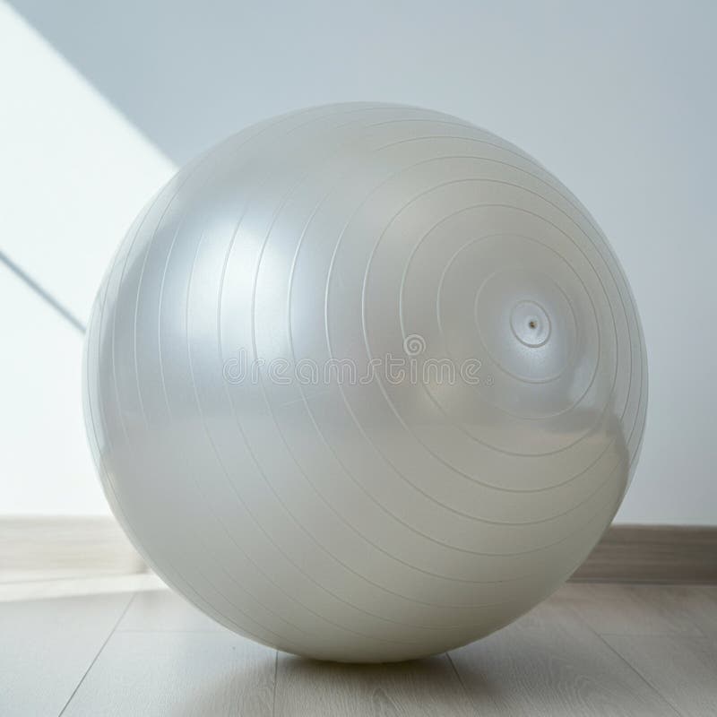 A Large, Gray Exercise Ball is Positioned on a Light Wood Floor Against ...