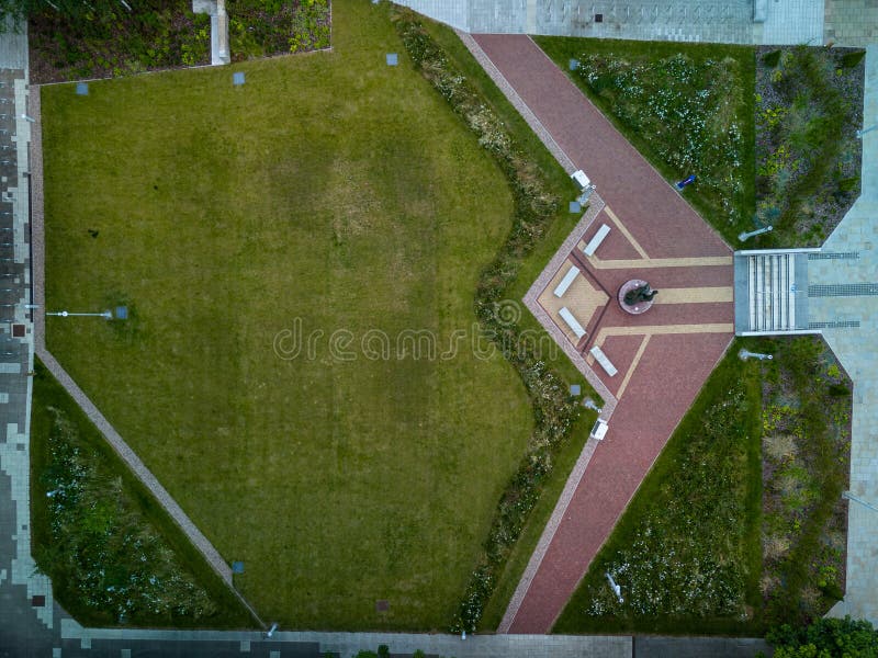 Large Green Square of Grass Surrounded by a Paved Path with Benches in ...