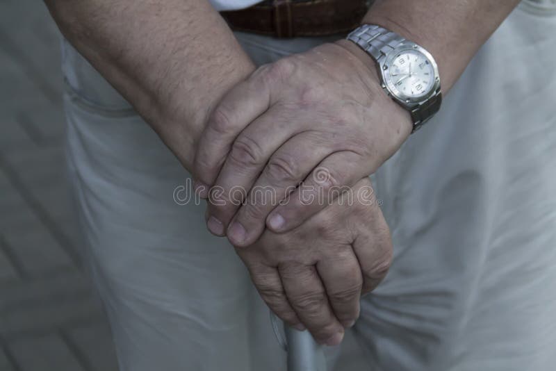 The Large Hands of an Elderly Man are Folded on a Cane with a Watch on ...
