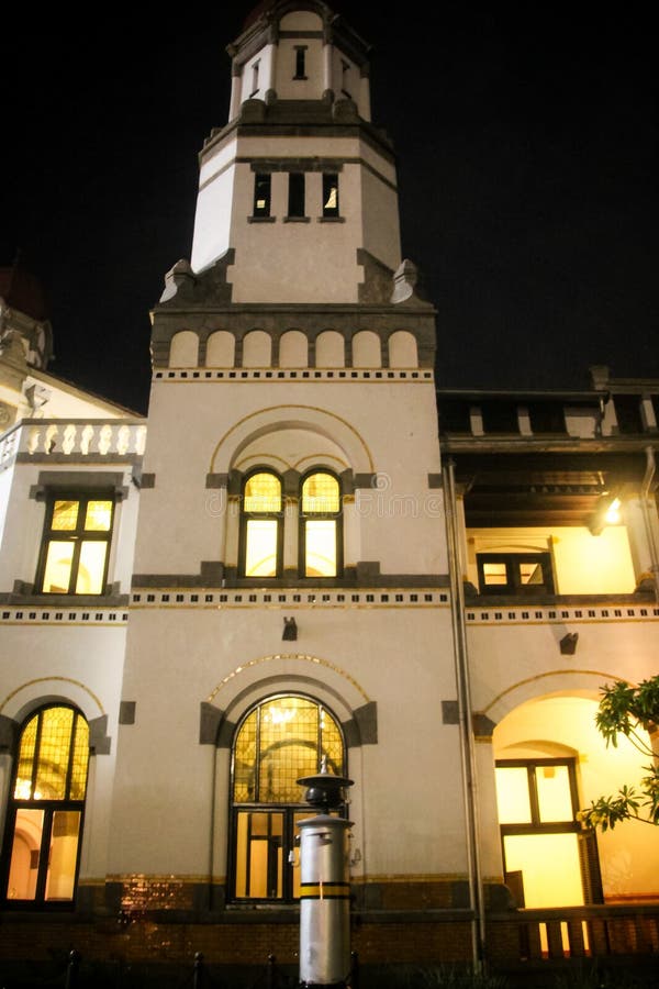 A Large House with Bright Lights is Seen in Front of a Tall Tower with ...