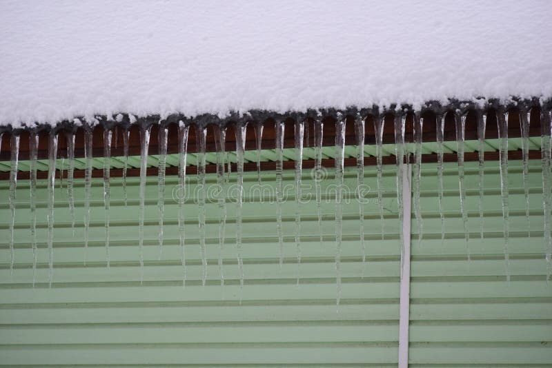 Large Ice Icicles Hang from Roof. Ice Falling Hazard Stock Photo ...