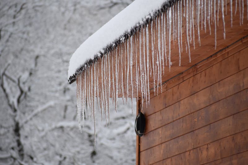 Large Ice Icicles Hang from Roof. Ice Falling Hazard Stock Photo ...