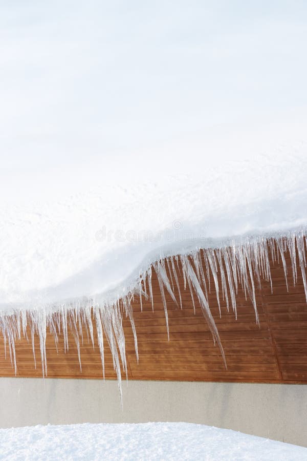 Large Icicles Hanging from a Building Roof Covered in White Winter Snow ...