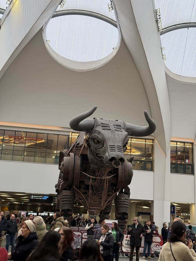 Large Mechanical Bull Sculpture in a Bustling Train Station with a ...