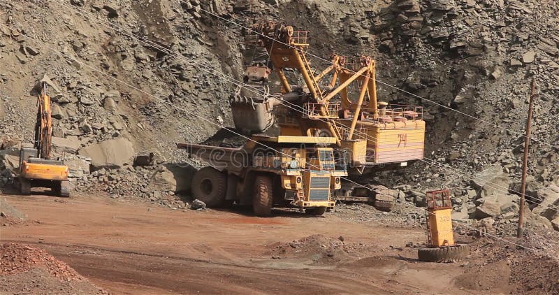 A Large Mining Excavator is Loading a Mining Truck in an Iron Ore ...