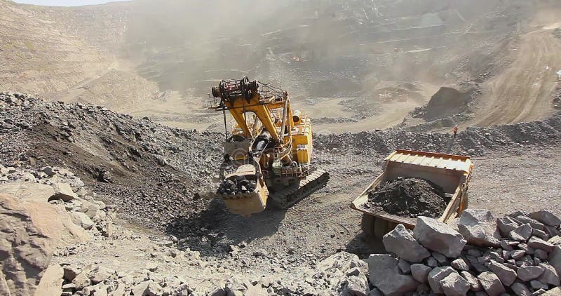 A Large Mining Excavator is Loading a Mining Truck in an Iron Ore ...