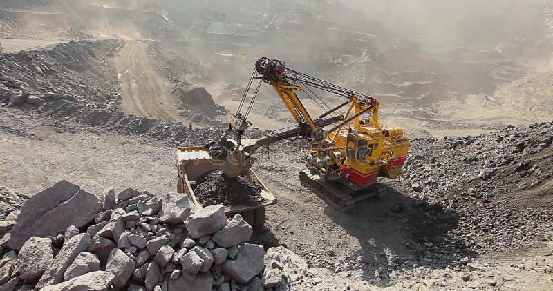 A Large Mining Excavator is Loading a Mining Truck in an Iron Ore ...