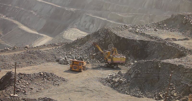 A Large Mining Excavator is Loading a Mining Truck in an Iron Ore ...