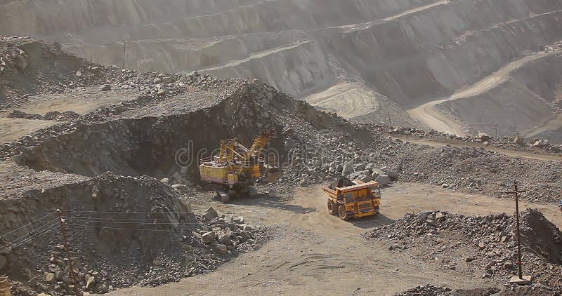A Large Mining Excavator is Loading a Mining Truck in an Iron Ore ...