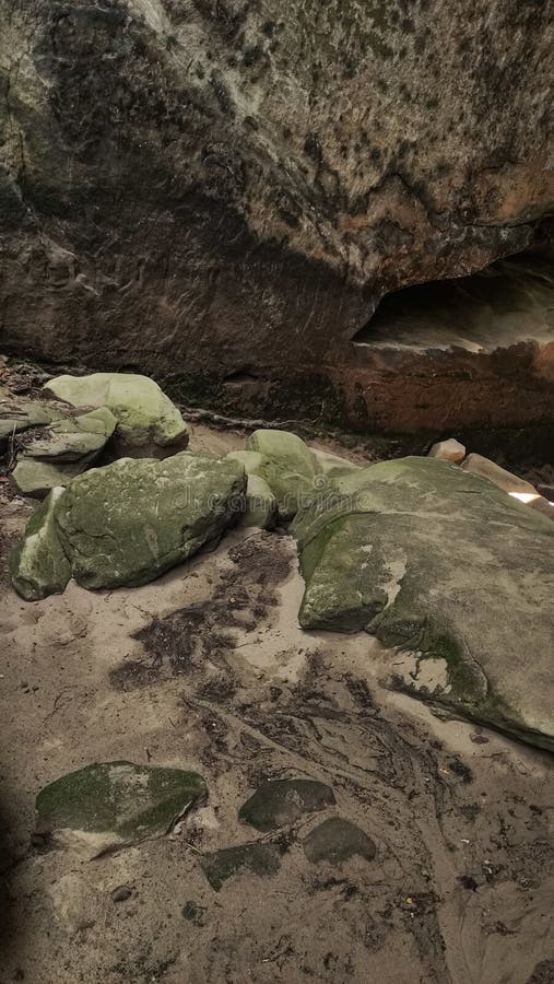 Large, Moss-covered Rocks Sit Beneath a Sandstone Overhang Stock Photo ...