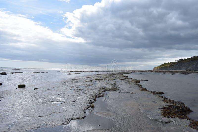 Mud Flat with Ocean Waves and Bright Cloudy Sky Stock Photo - Image of ...