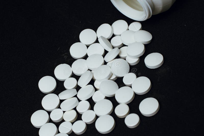A Large Number of White Tablets Scattered from the Container on a Black ...
