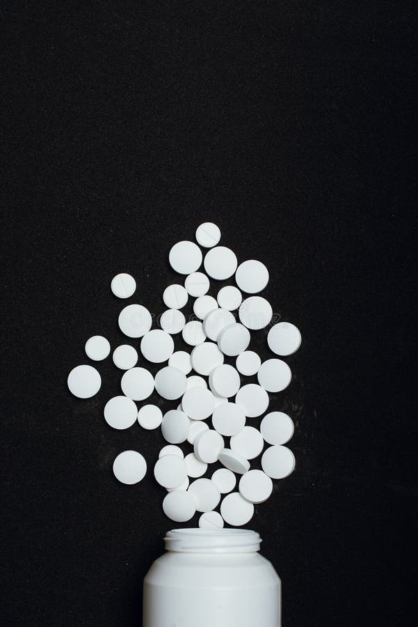 A Large Number of White Tablets Scattered from the Container on a Black ...