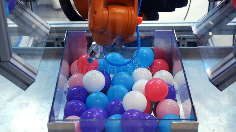Large Orange Robotic Hand Relocating Small Plastic Multicolored Balls ...