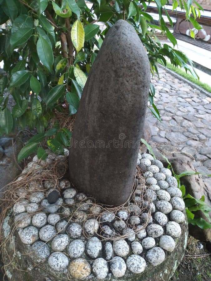 A Large Oval Stone Surrounded by Small White Stones in Front of a Small ...