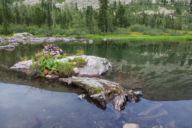 A Large Overgrown Rock in the Middle of a Mountain Lake Stock Photo ...