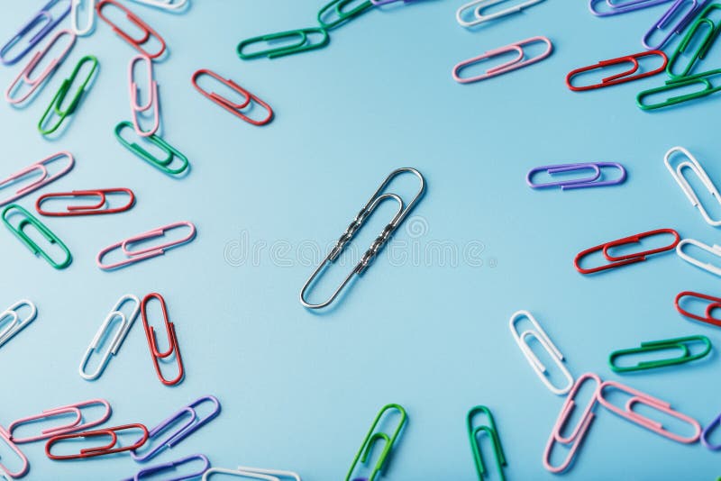 A Large Paper Clip Surrounded by Small Colored Paper Clips on a Blue ...
