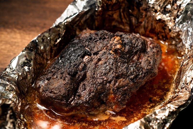A Large Piece of Baked Meat with Spices Wrapped in Foil in the Oven ...