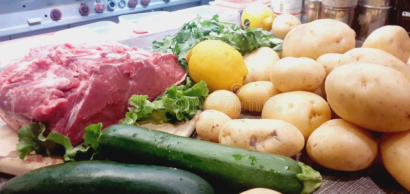 Large Piece of Raw Meat with Potatoes, Zucchini, Lemons and Salad Stock ...