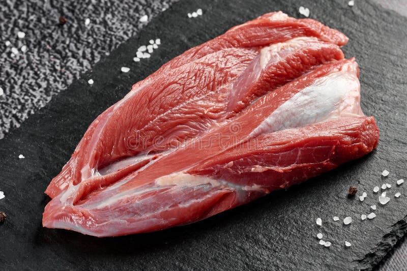 A Large Piece of Red Beef Meat on a Black Stone Background with Salt ...