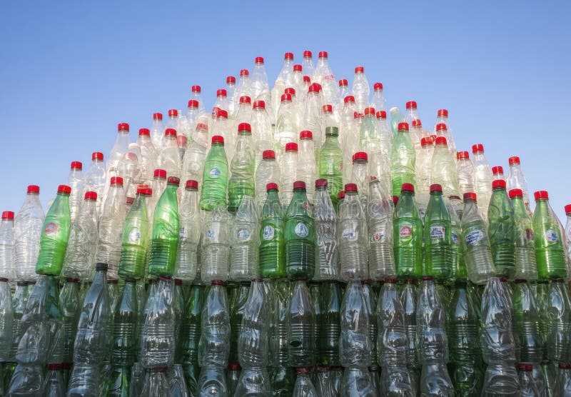 Pyramid of Translucent Green and Clear Plastic Bottles Against a Blue ...