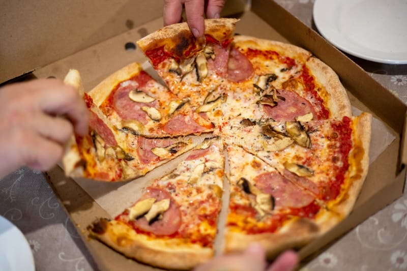 Large Pizza on the Table in a Box, Cut into Pieces, Which People Take ...