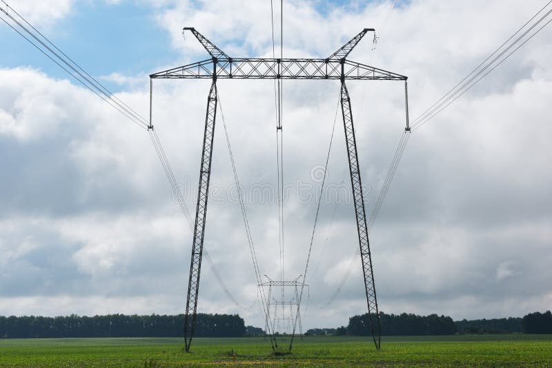 A Large Power Line Post Against the Sky with Clouds in the Backlight ...
