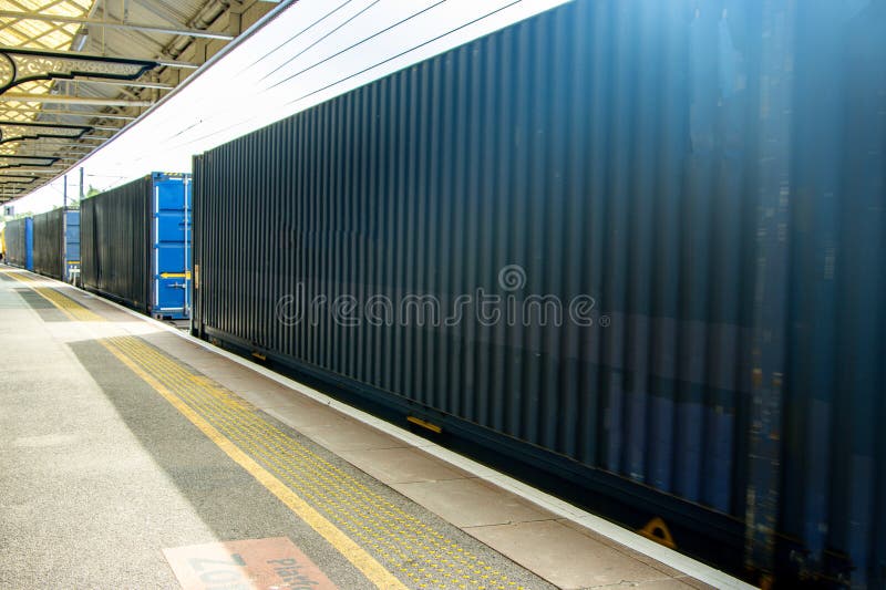 A Large and Powerful Freight Train Passing by a Station Platform ...