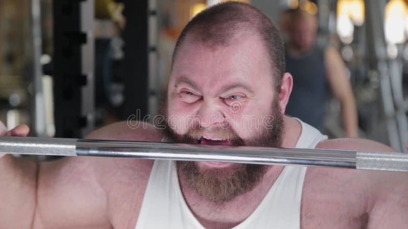 A Large and Powerful Weightlifter Bites the Barbell Angrily before ...