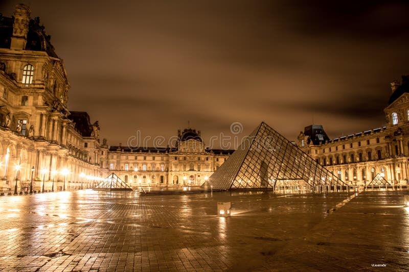 Large Pyramid in a Courtyard Lit Up at Night in Front of Buildings ...