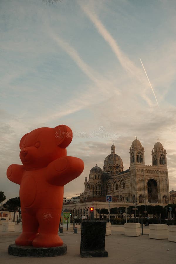 Large Red Cartoon Bear Statue in Front of a Large Old Cathedral with ...