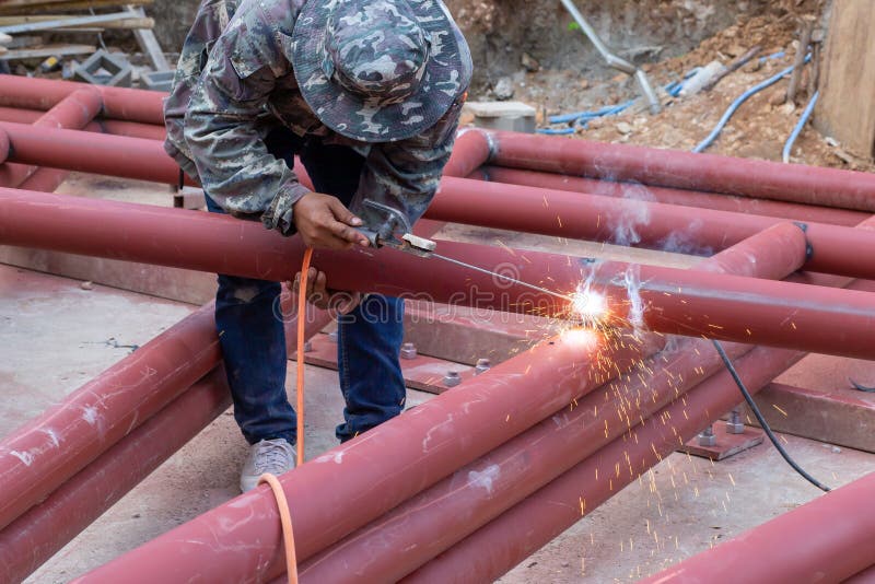 A Large Red Iron Pole Being Welded by a Welder on the Construction Site ...